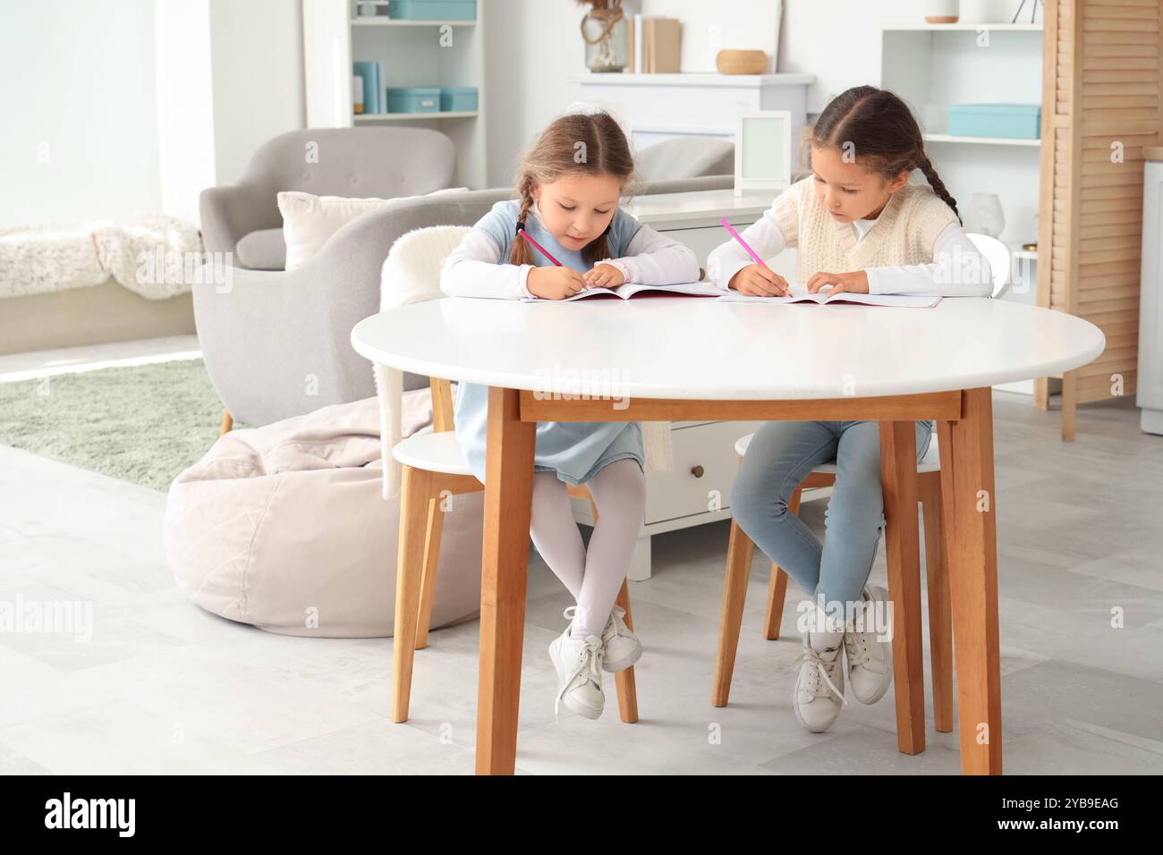 Cute little girls writing in copybooks at home Stock Photo - Alamy