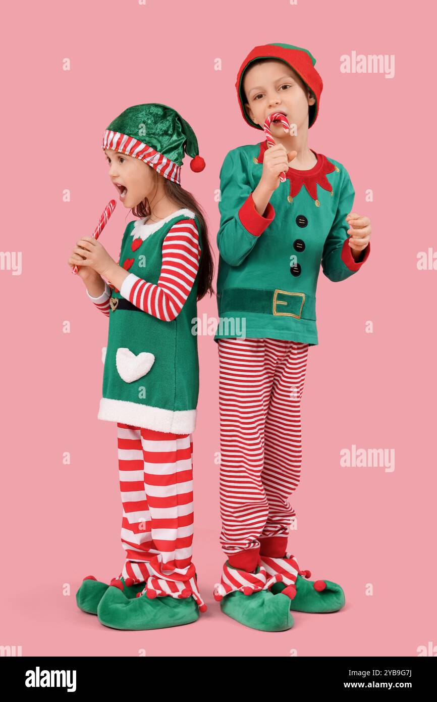 Cute little children in elf's costumes with candy canes on pink ...