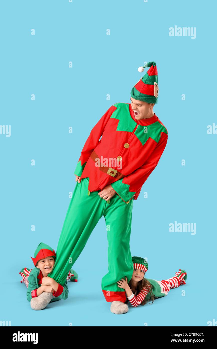 Father and cute little children in elf's costumes on blue background ...
