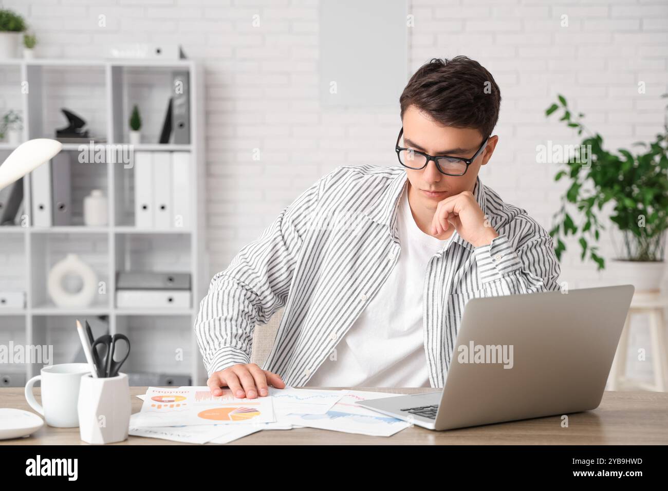 Male economist working with diagrams at table in office Stock Photo - Alamy