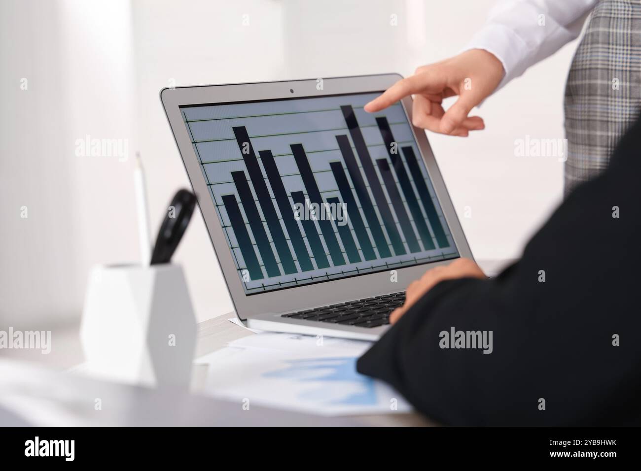 Male economist and secretary working with diagrams on laptop in office ...