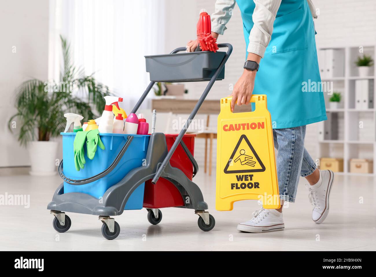 Janitor with trolley and caution sign in office Stock Photo - Alamy