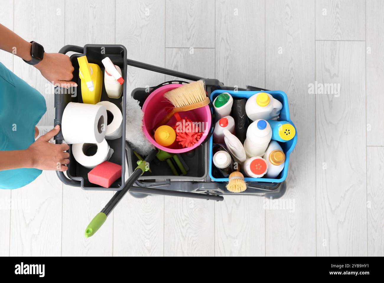 Janitor pushing trolley with cleaning supplies, top view Stock Photo ...