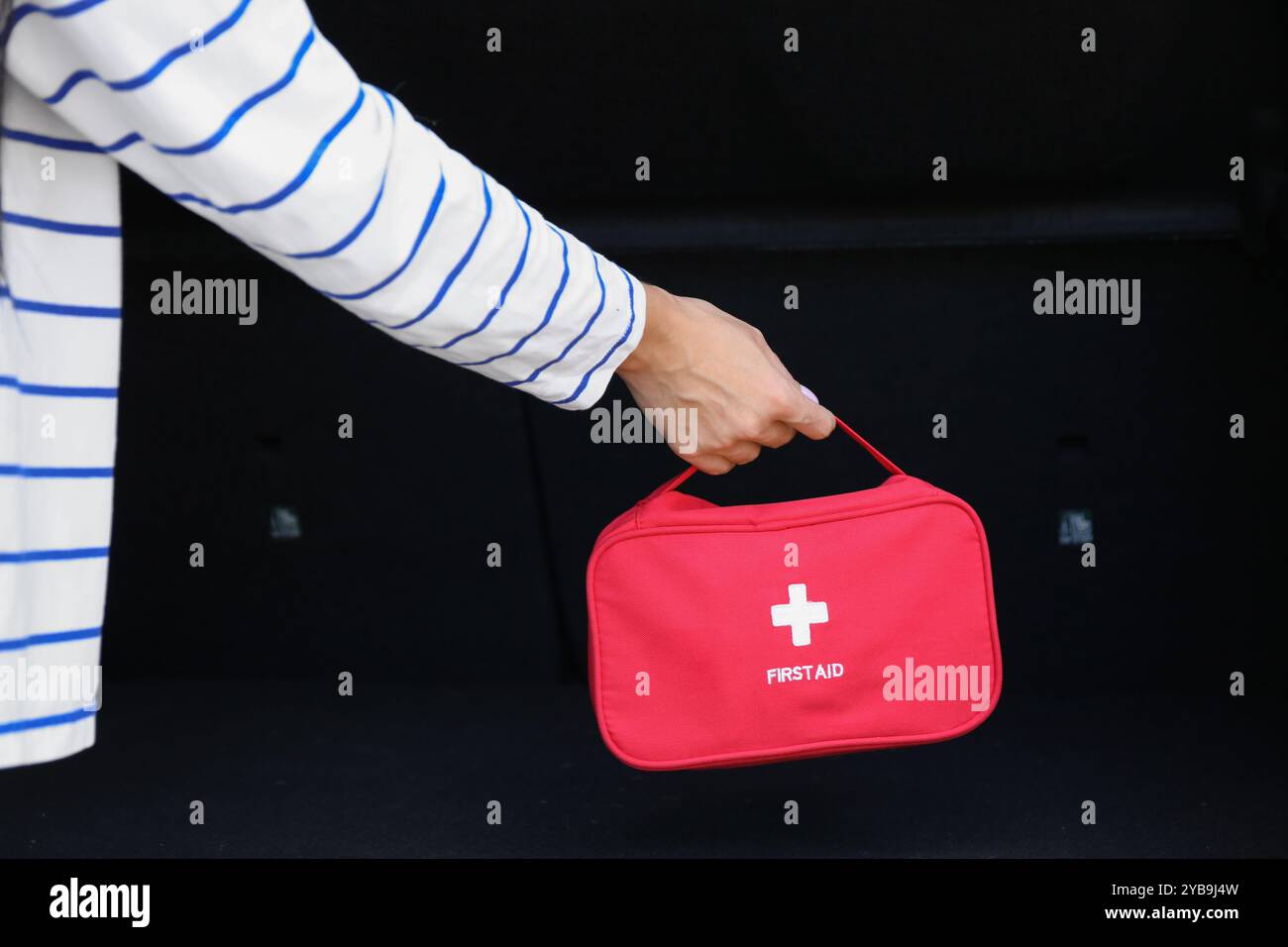Driver putting first aid kit in car trunk Stock Photo - Alamy