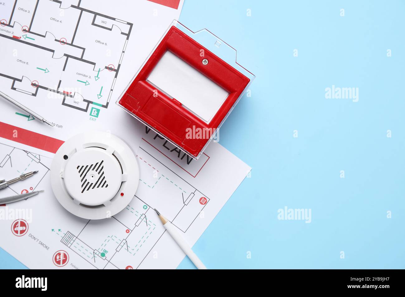 Modern smoke detector with fire call point and evacuation plans on blue ...