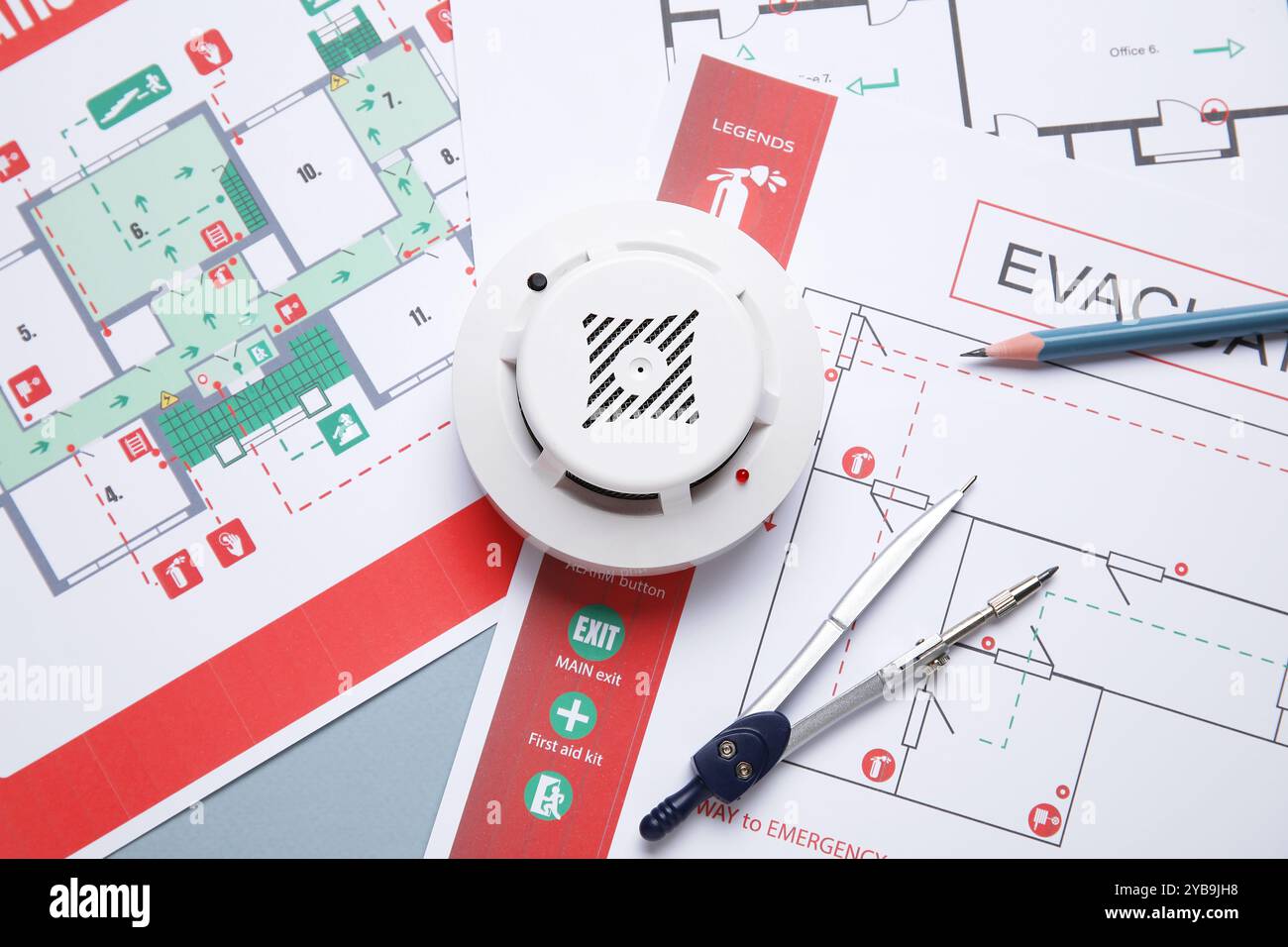 Modern smoke detector with pair of compasses and evacuation plans on ...