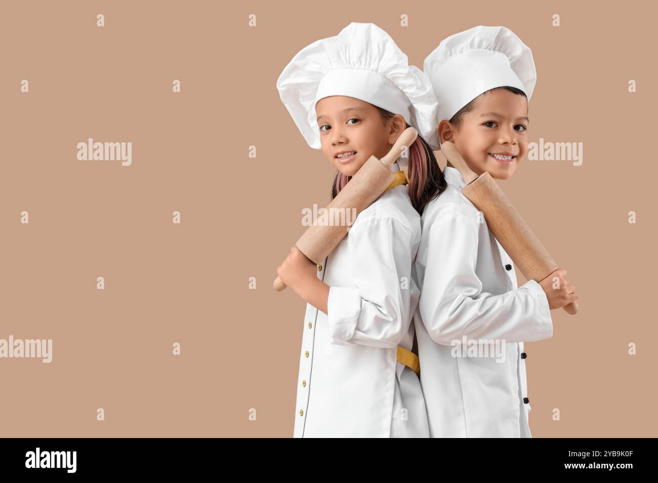 Cute little Asian chefs with rolling pins on beige background Stock ...