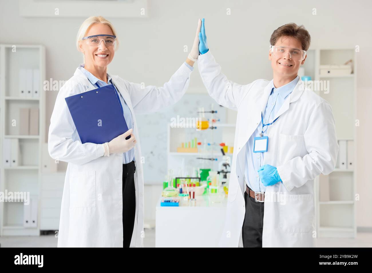 Chemists giving each other high-five in laboratory Stock Photo - Alamy