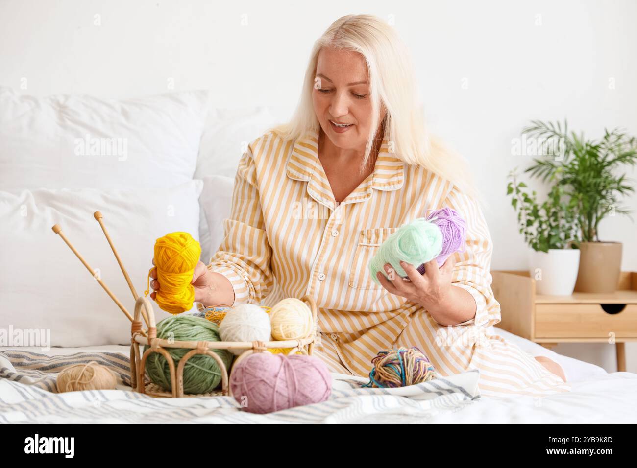 Mature woman with knitting yarn sitting in bedroom Stock Photo - Alamy