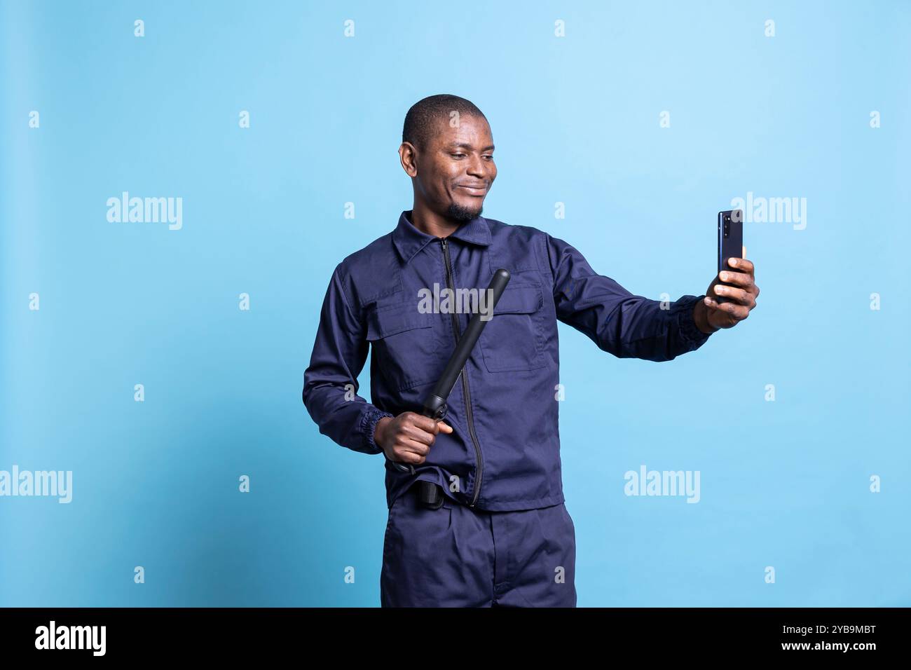 Serious security agent enjoys taking photos against blue background ...