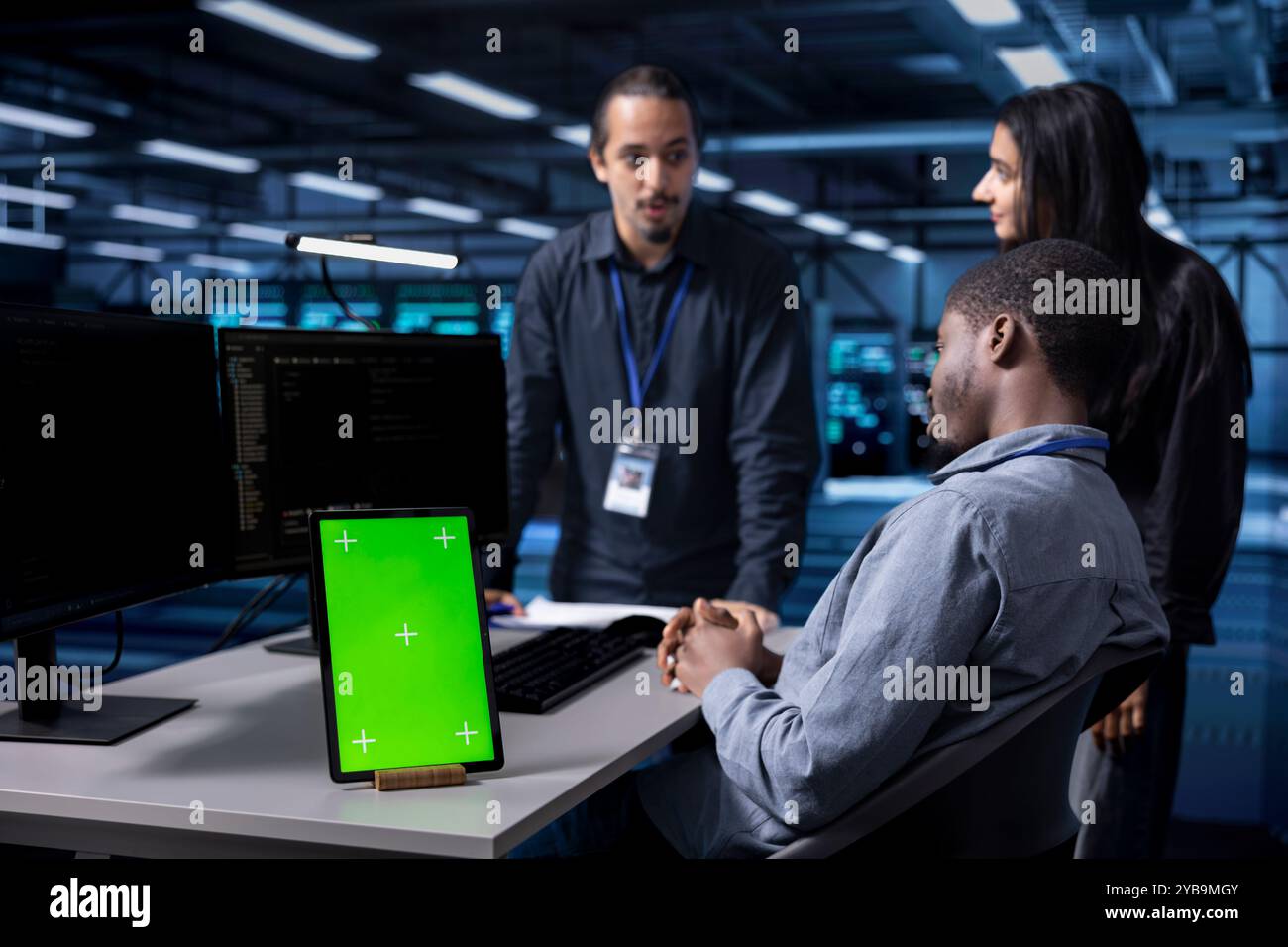 Multiethnic engineering team works on green screen tablet in data ...