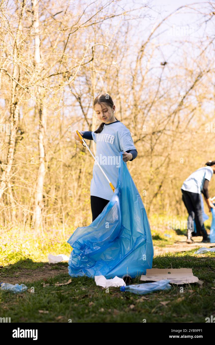 Little child grabbing waste an junk with a claw tool and collecting ...
