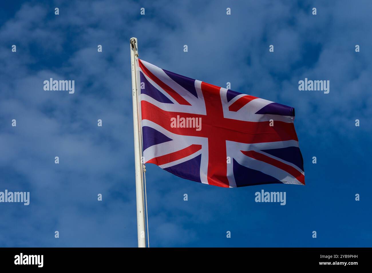 A Union Jack flag flutters on a flagpole, displaying its vibrant red ...