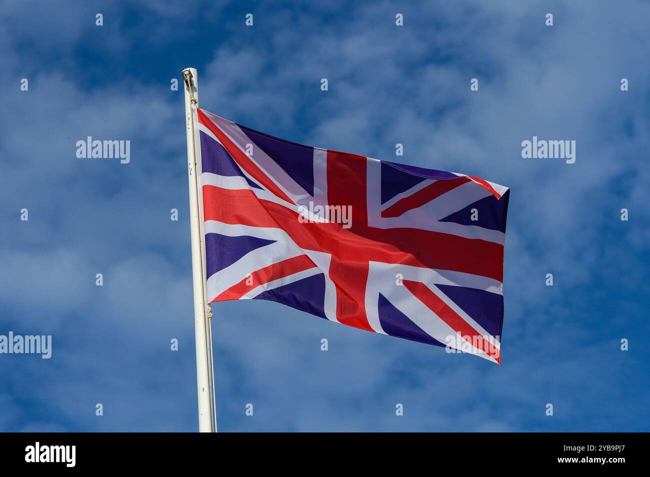 A vibrant Union Jack flag flutters atop a flagpole, set against a ...