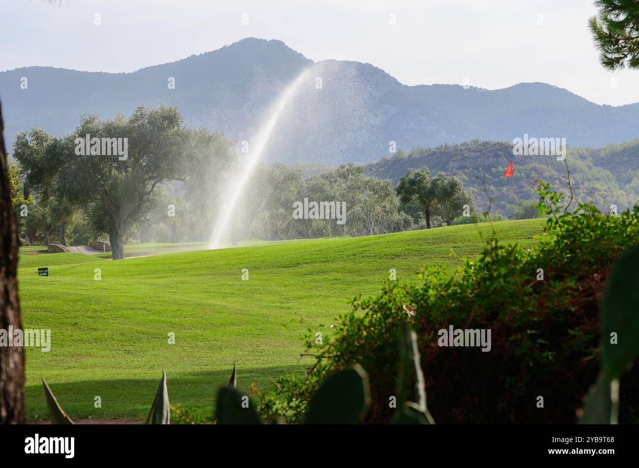 A tranquil golf course awaits as a fountain sprays water, casting a ...
