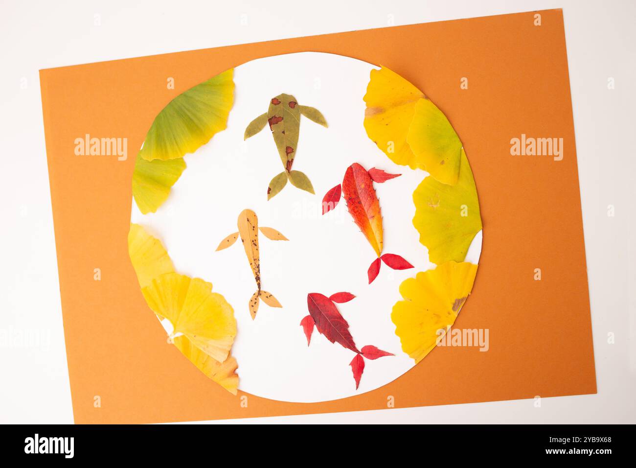 Autumn leaf art depicting fish in a circular pattern with yellow ginkgo ...