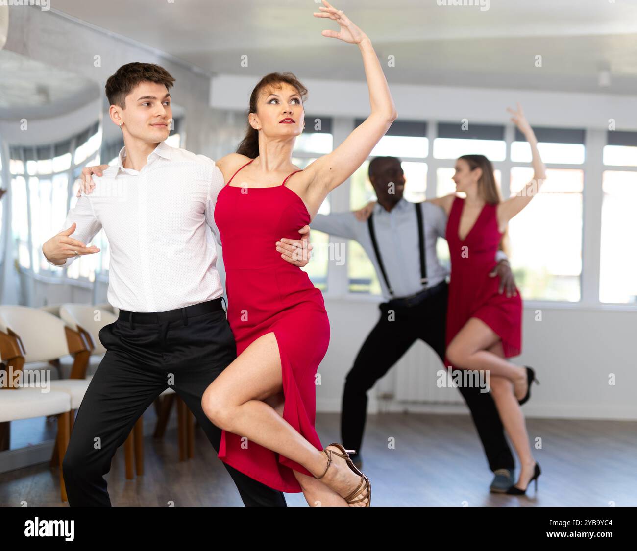 Happy man and woman in elegant red clothes enjoying ballroom dancing ...