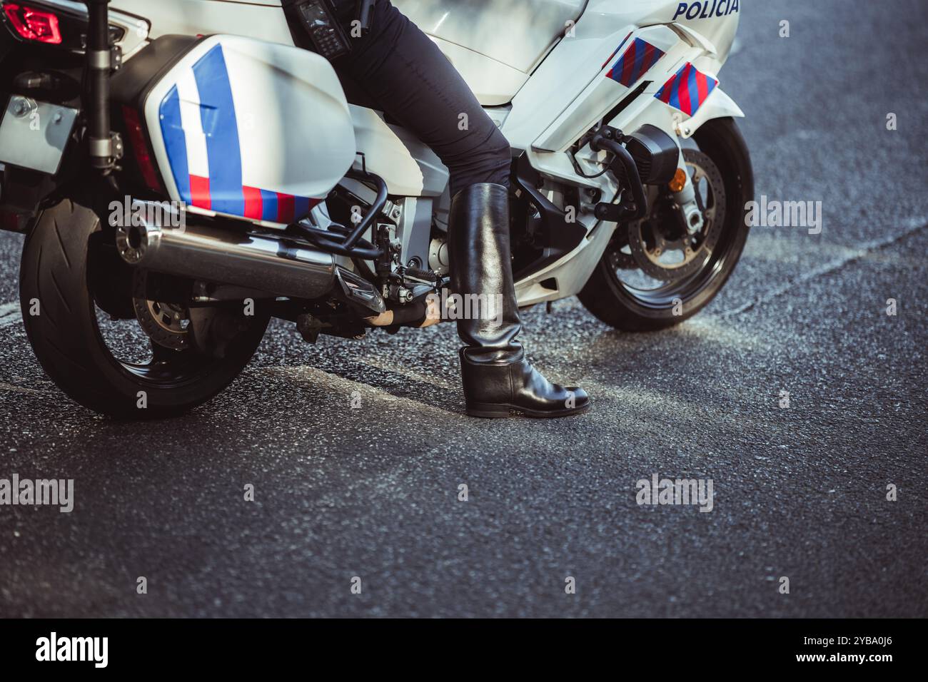 A police officer on a white motorcycle is parked on a road. The image ...