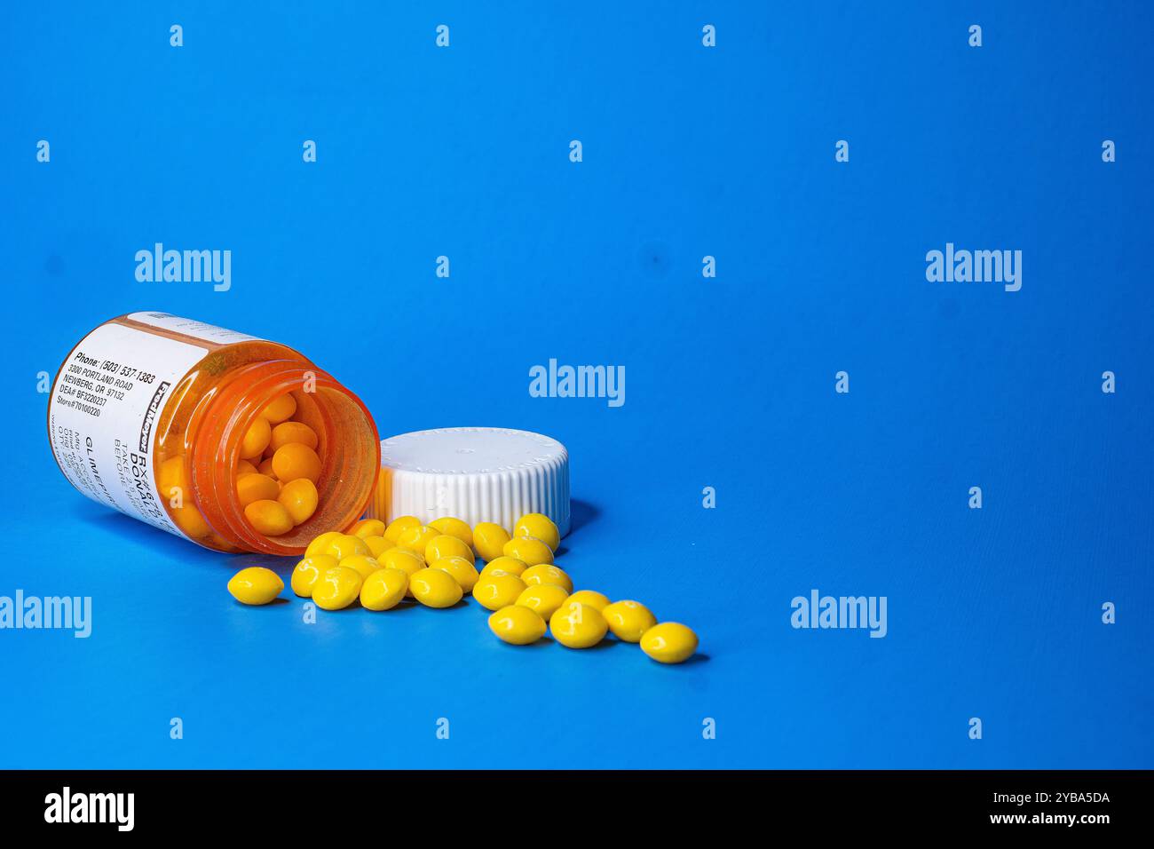 An open bottle of prescription drugs containing orange tablets. Cap is ...