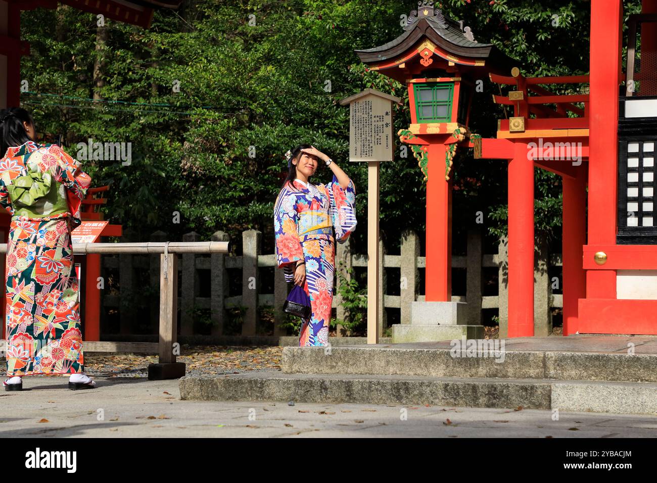 Two female visitors in Kimono taking photograph in Fushimi Inari-taisha ...