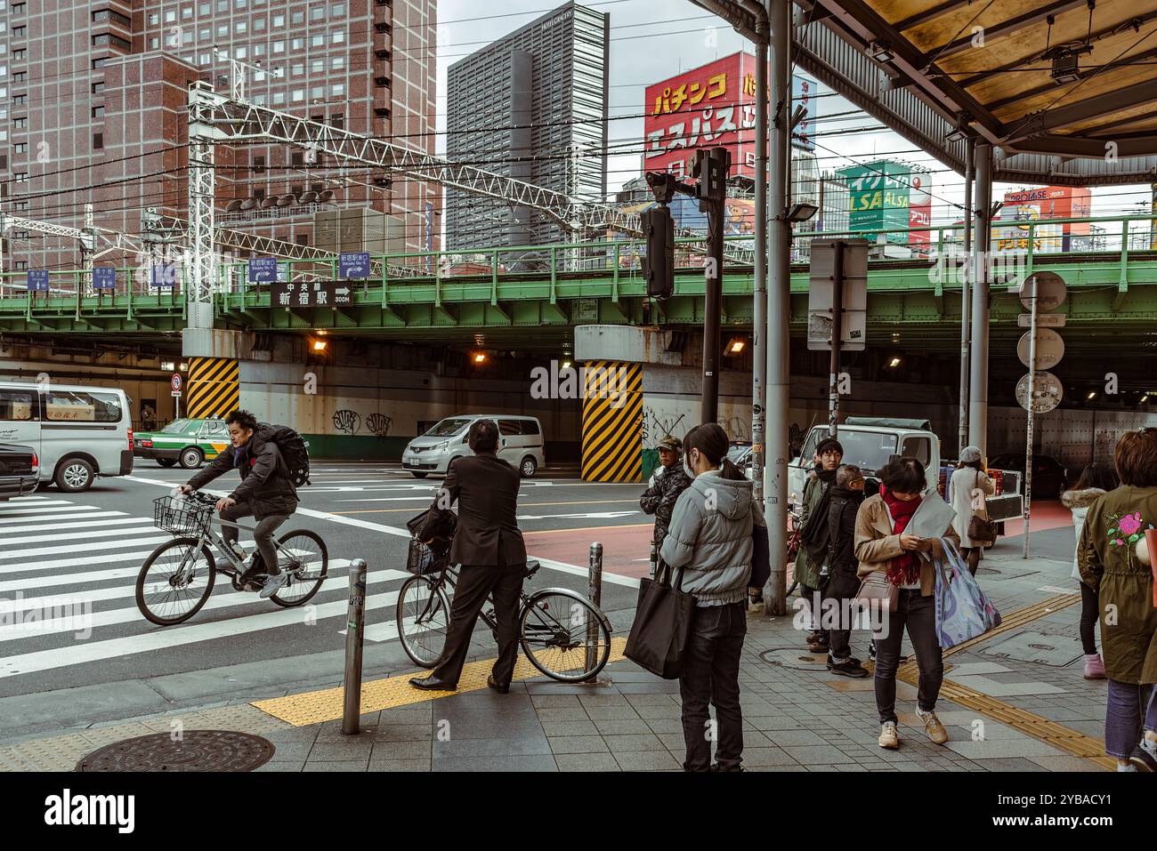 Pedestrians and cyclists cross busy road, downtown Shinjuku, Tokyo ...