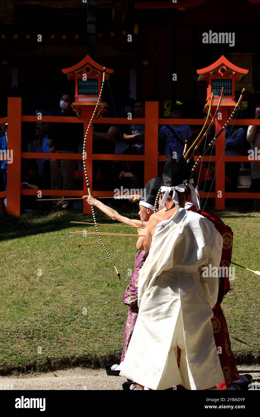 Male archers in traditional ceremonial robe and head piece aiming at ...
