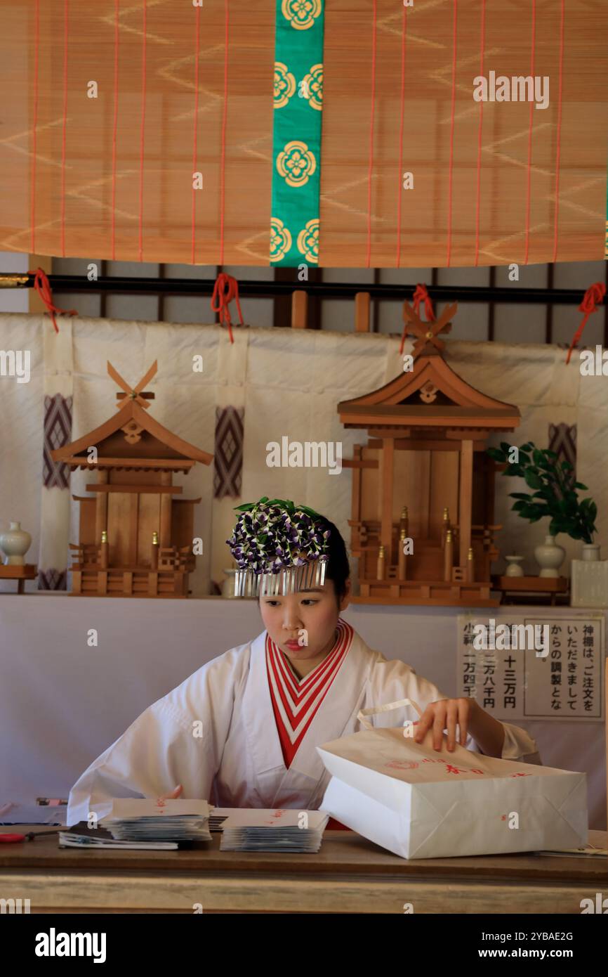 A female worker in traditional ceremonial robe and head piece preparing ...