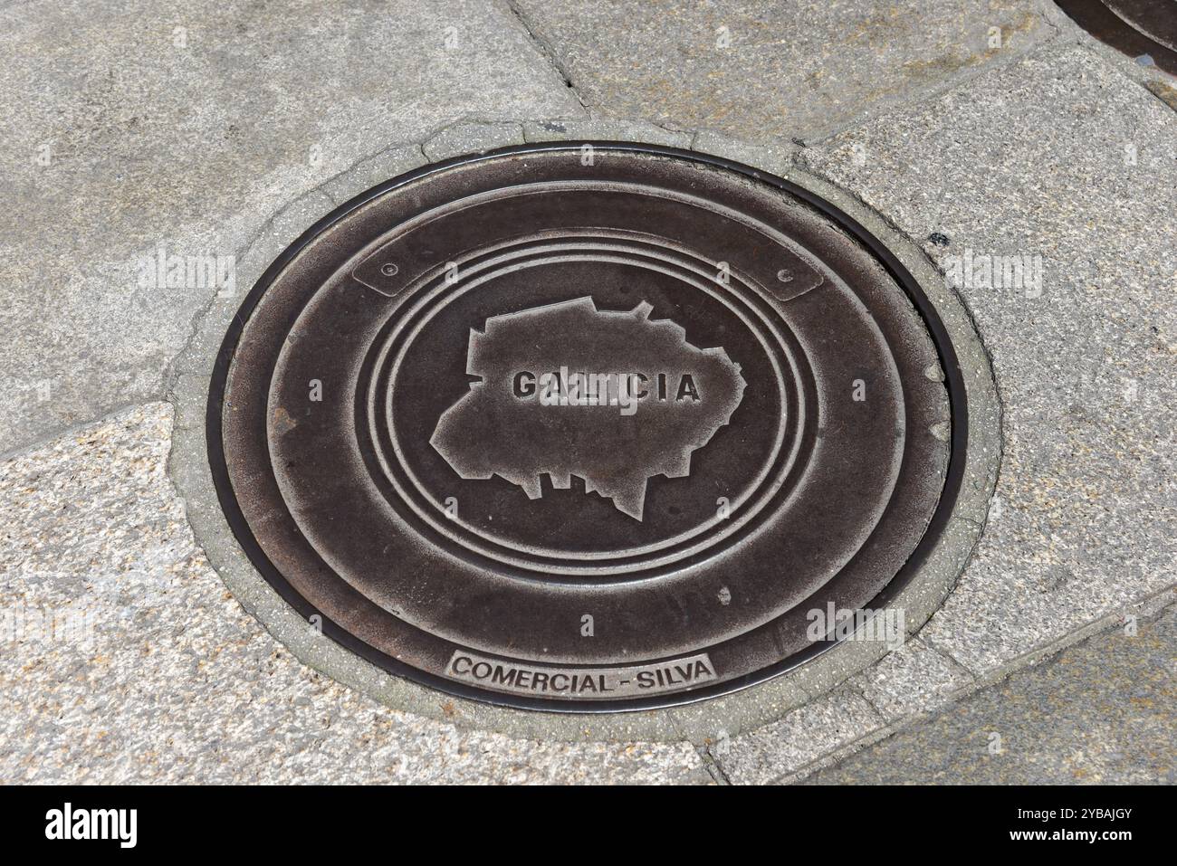 Metal manhole cover with the inscription 'Galicia' and outline of a map ...