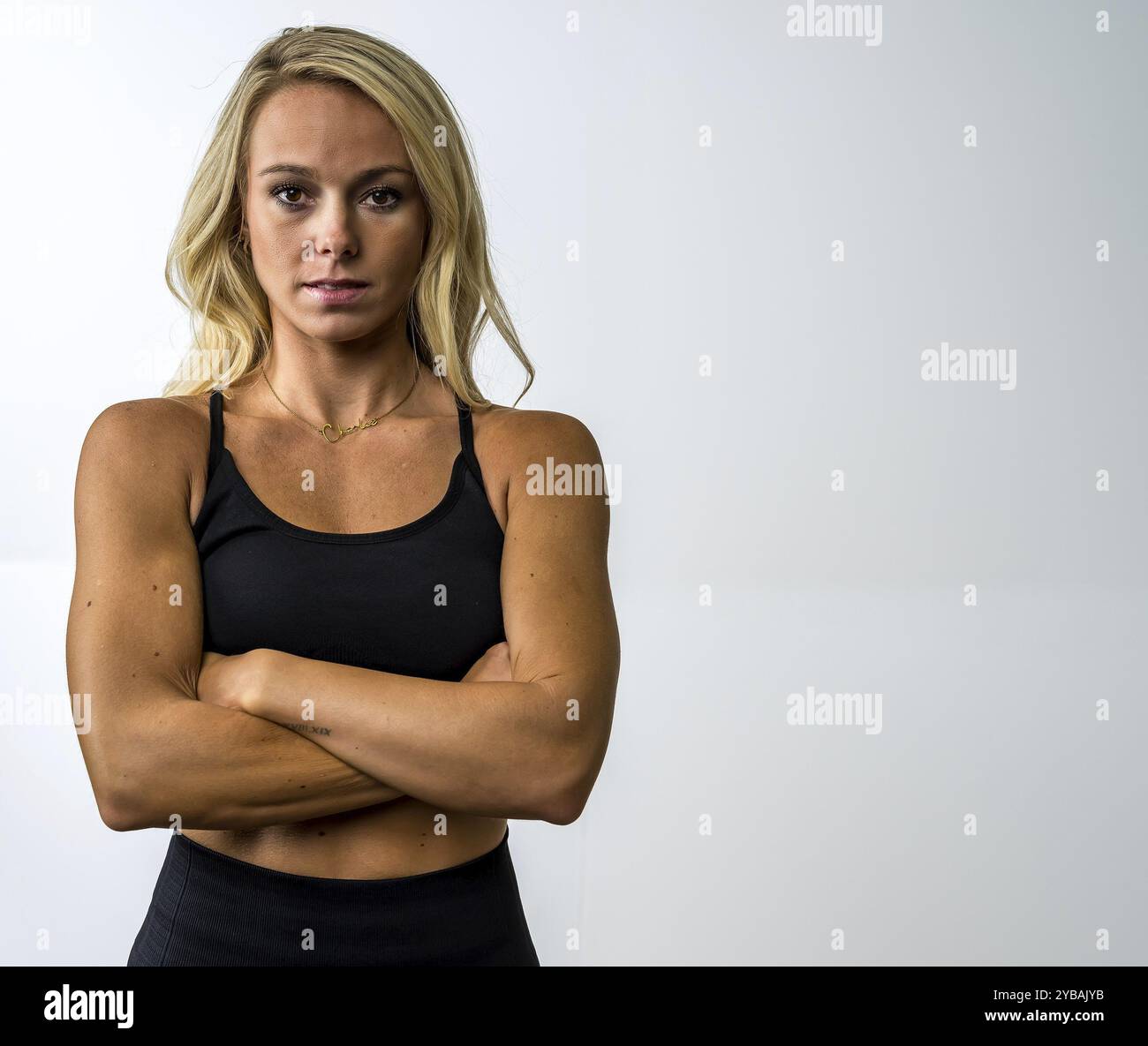 A gorgeous athletic fit model poses confidently in a studio, her toned muscles highlighted by ...