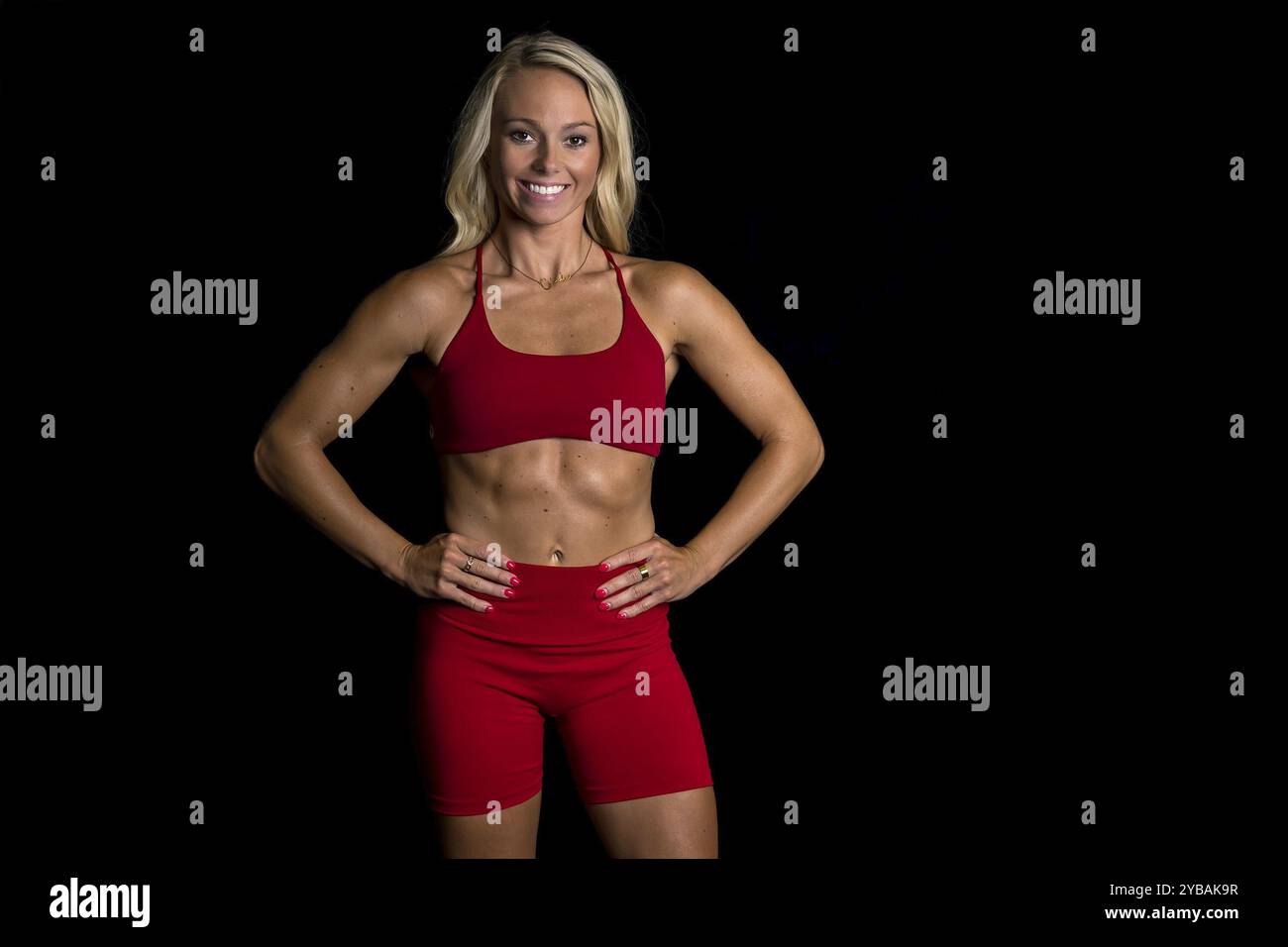 A gorgeous athletic fit model poses confidently in a studio, her toned muscles highlighted by ...