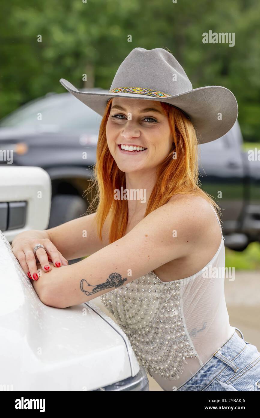 A beautiful redhead model poses in a country setting wearing cowgirl ...