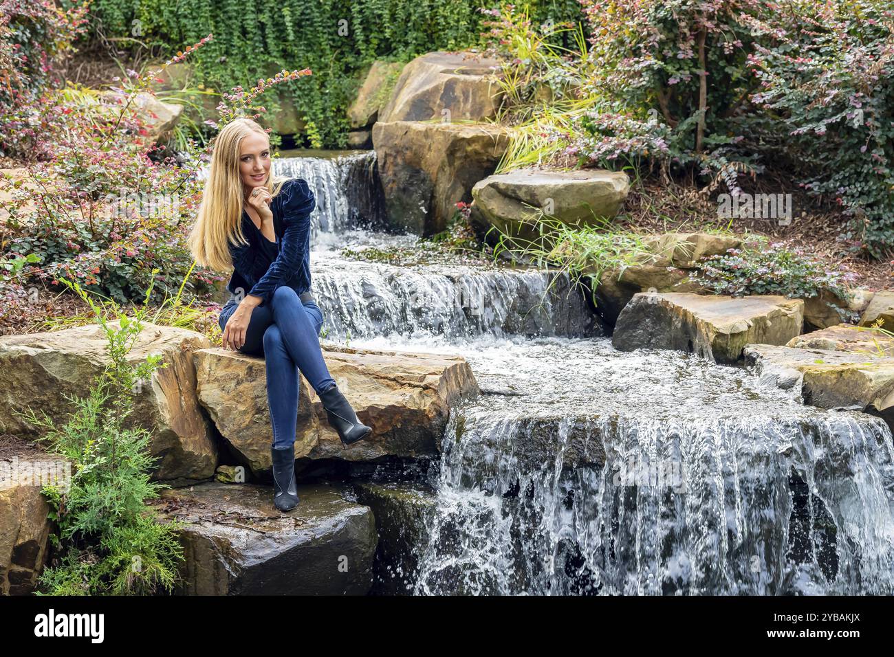 Blonde beauty shines in stunning fall attire near park waterfall, a ...
