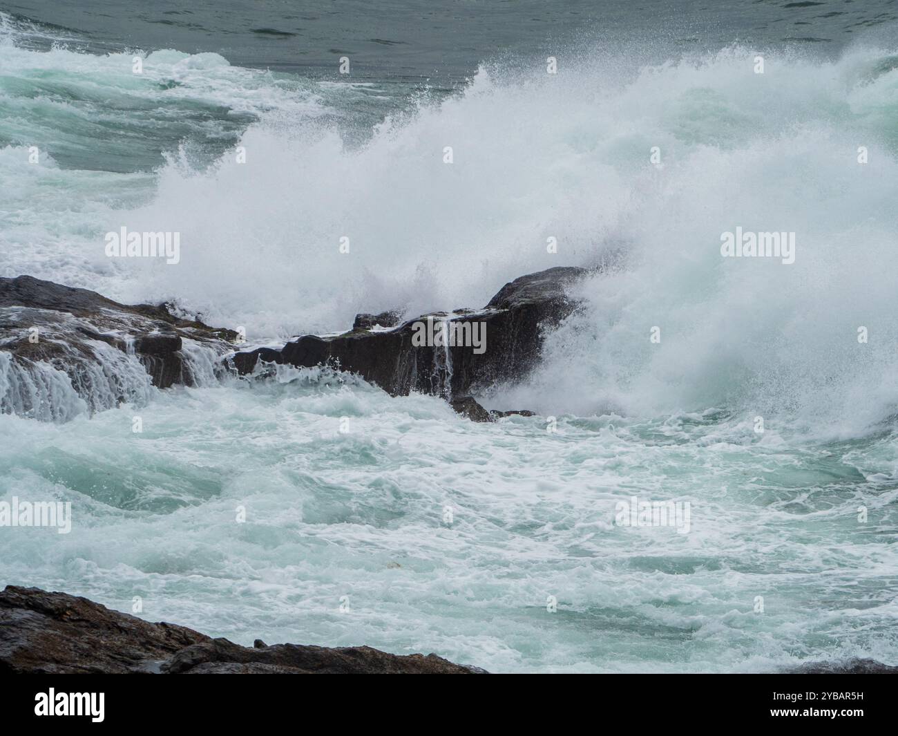 Powerful waves crashing over rocks, sea spray flying up into the air ...