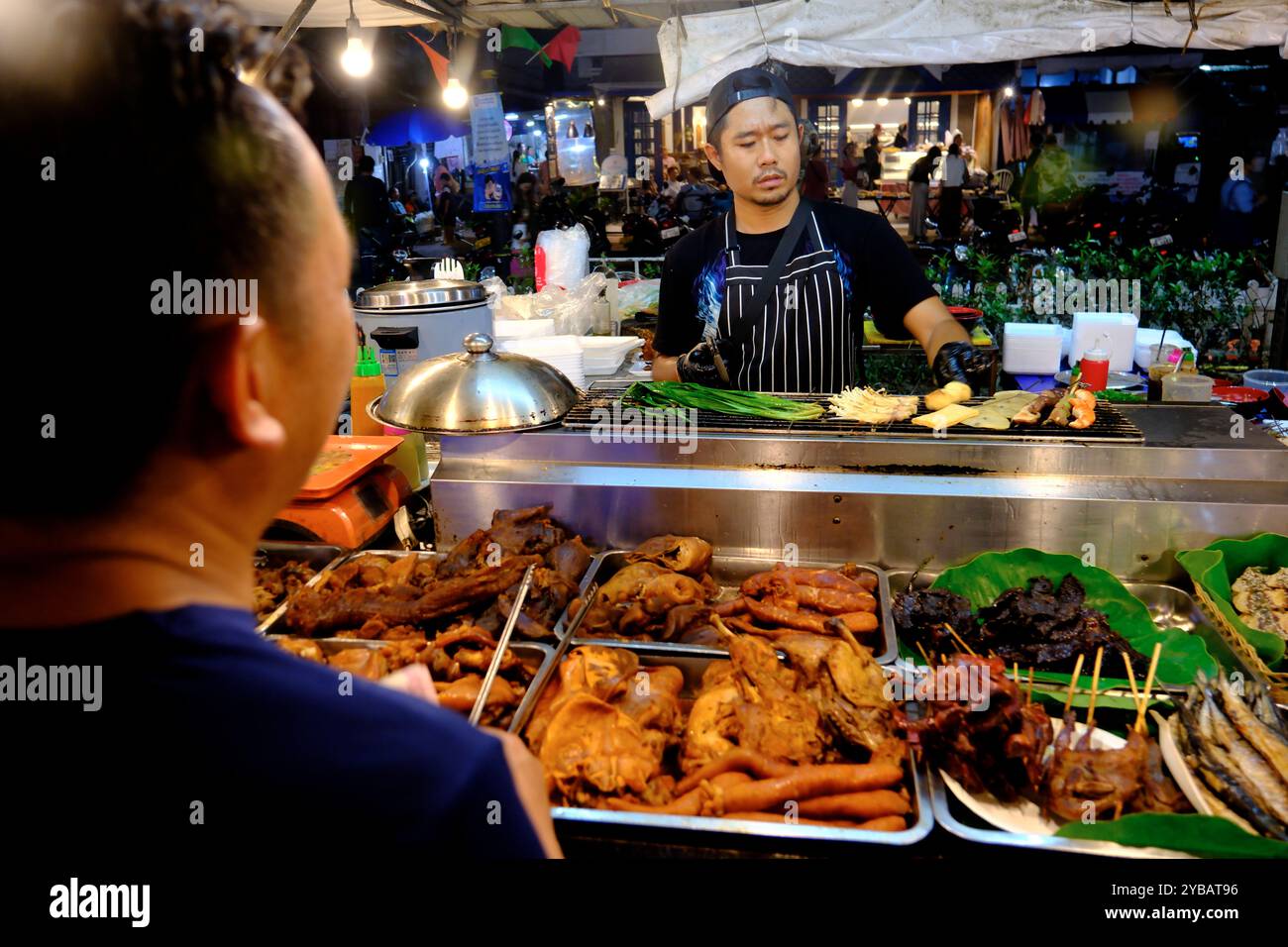 A male food vendor selling grilled meat in the Night Market of Luang ...