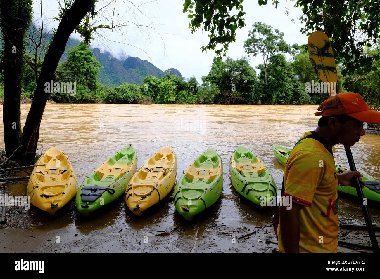Kayaks docking on the shore of Nam Song River with a caretaker holding ...