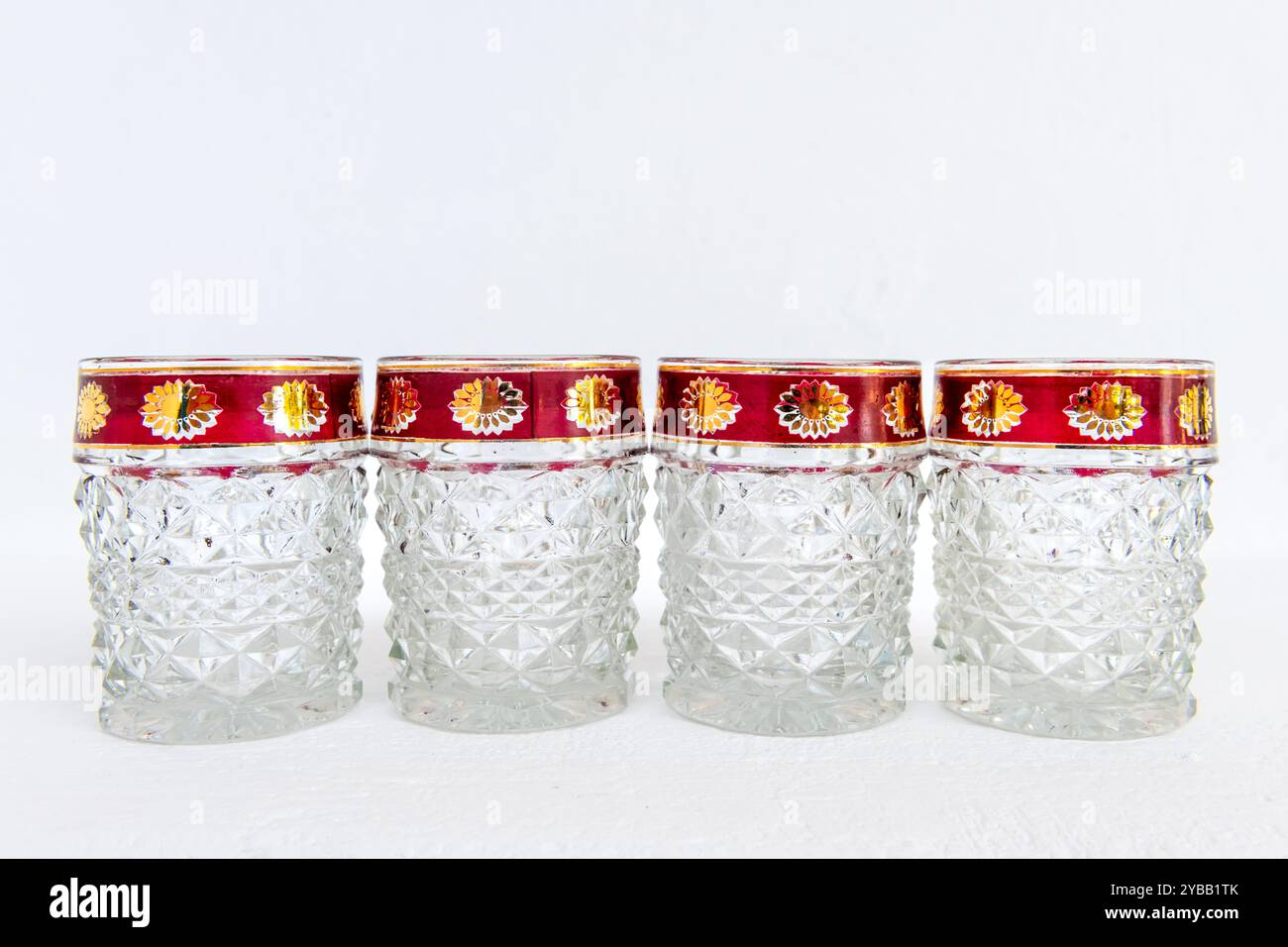 A row of vintage crystal glass cups with decorated rims, isolated on a ...