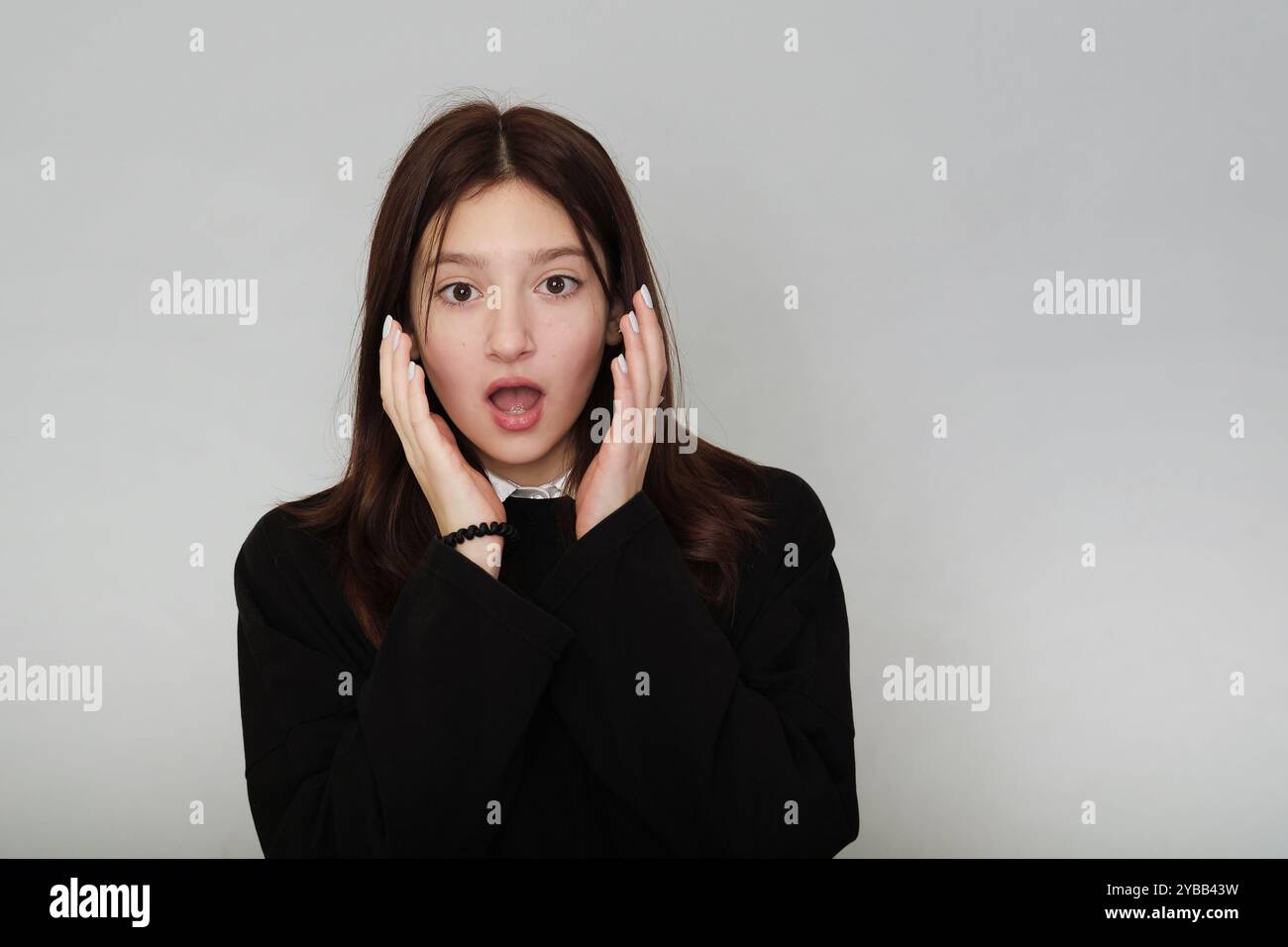Surprised young lady with hands on face, mouth agape. Reflects genuine ...