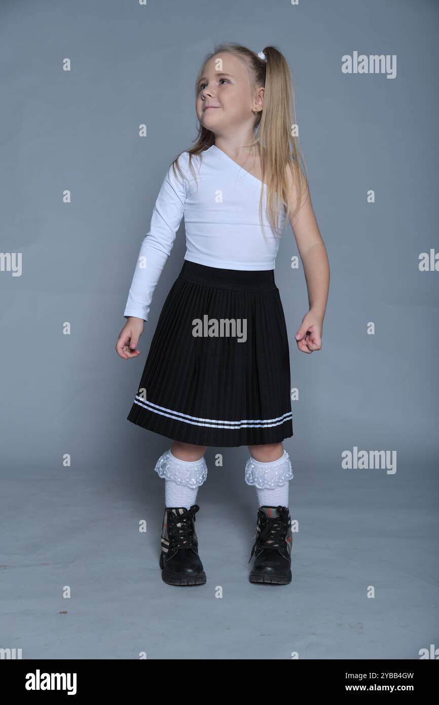 A poised 5-year-old girl stands in a studio, dressed in a fashionable ...