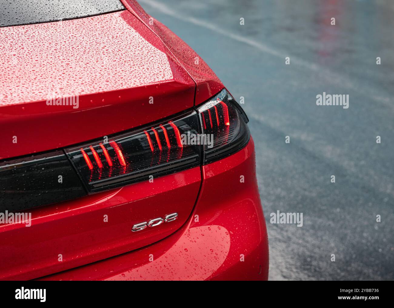 Tail light of Peugeot 508 on rainy day. Rear right corner of red french ...