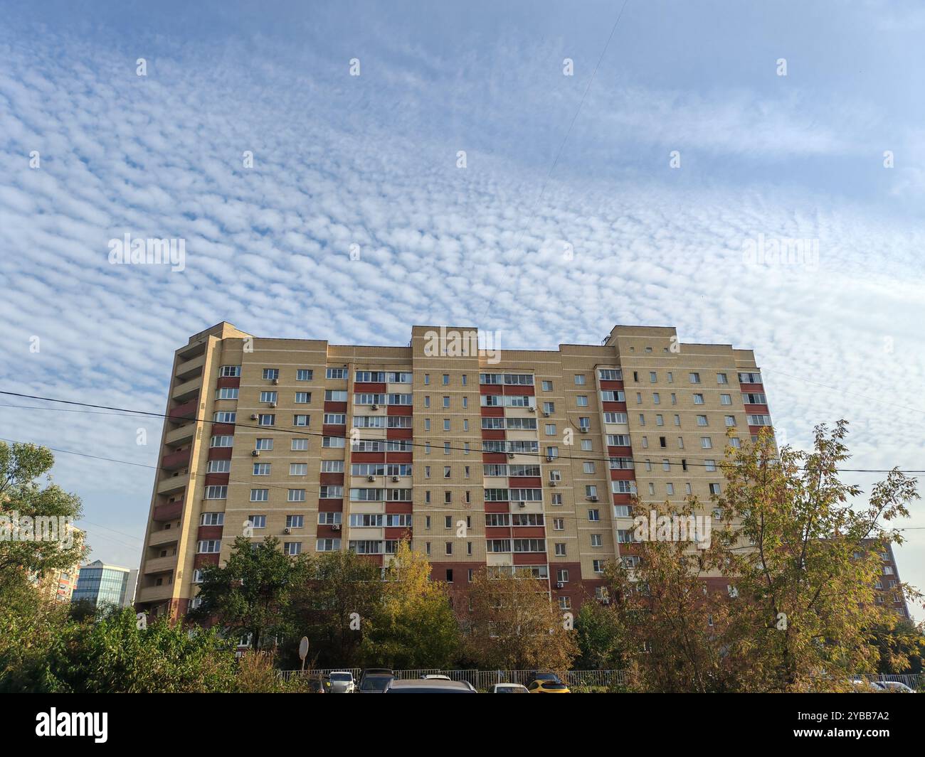A tall red and beige brick residential building with multiple balconies ...