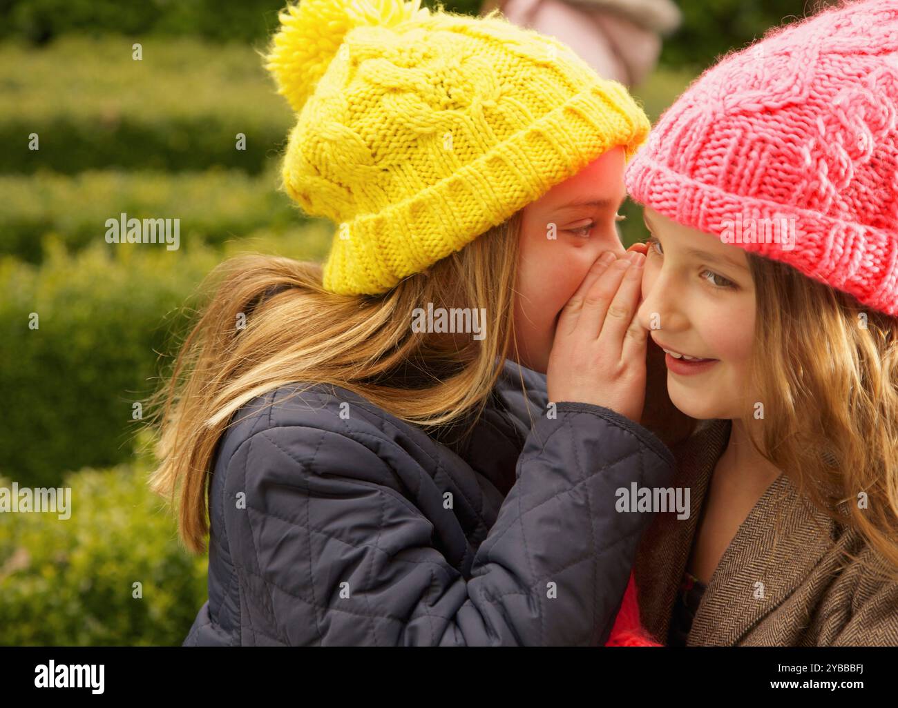 Young Girl Whispering in Friends Ear Stock Photo - Alamy