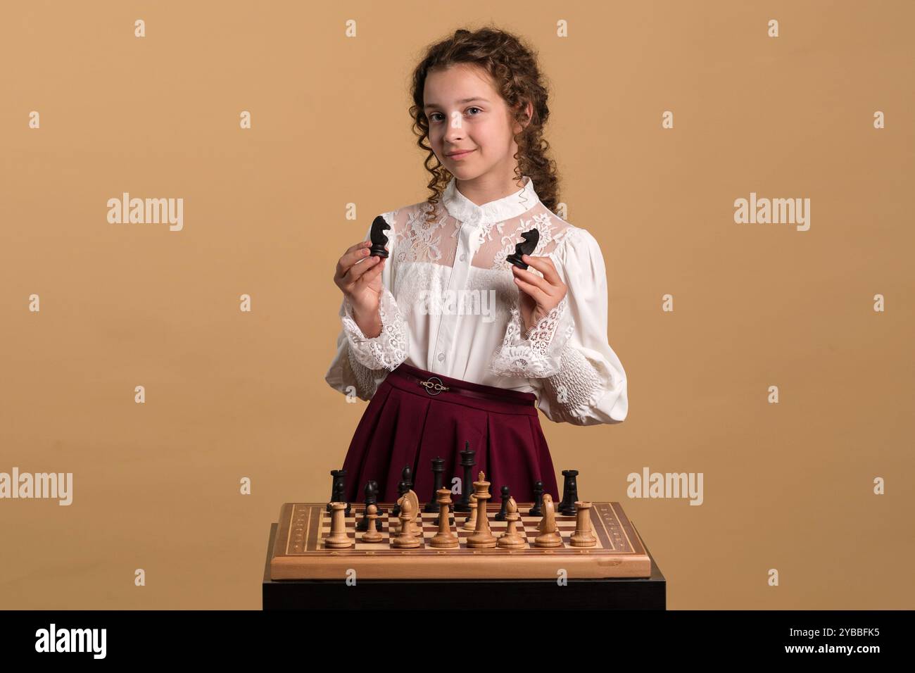 Young girl chess player displaying two black chess knights confidently ...