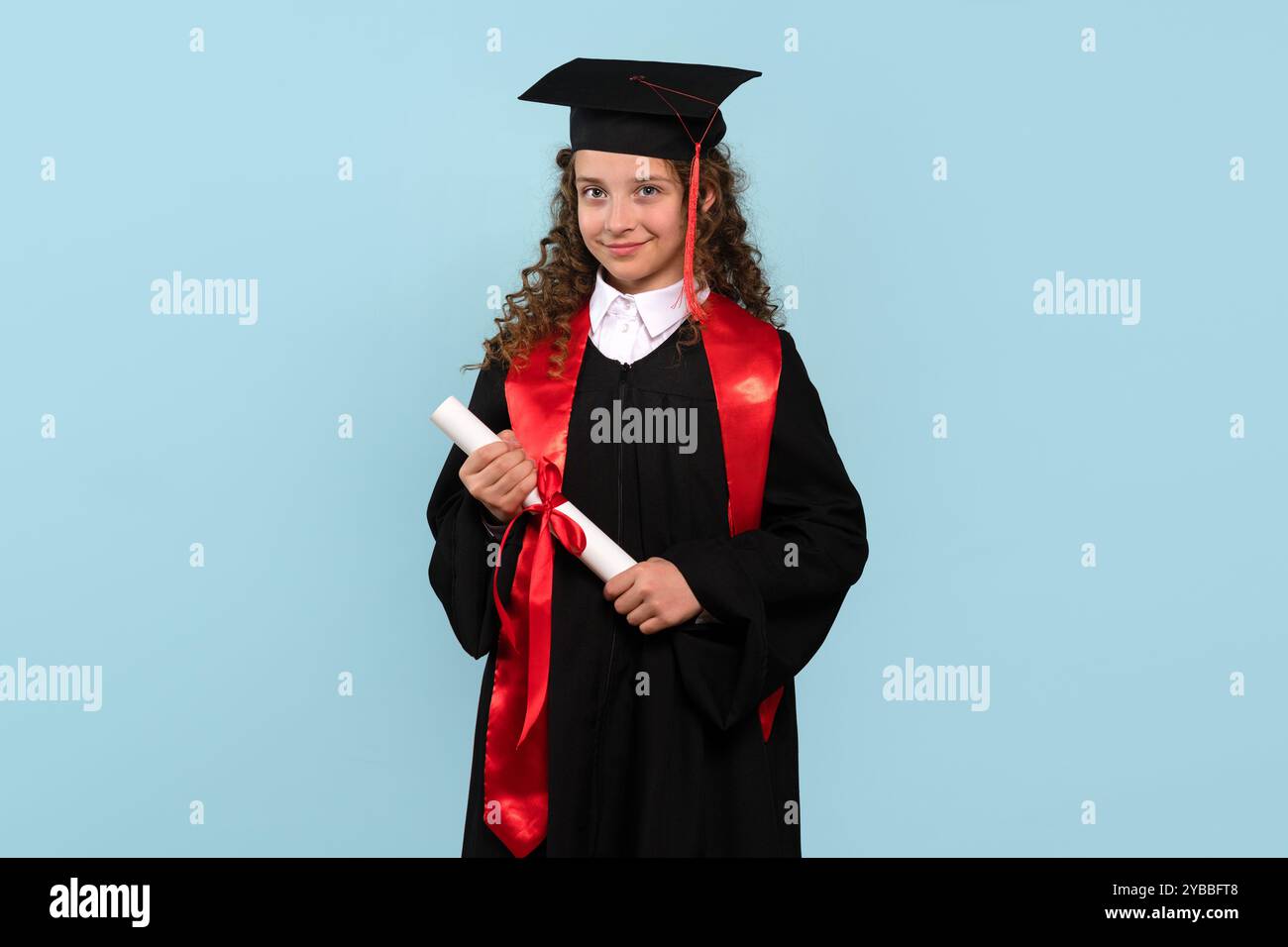 Young girl in graduation attire holding a diploma and smiling ...