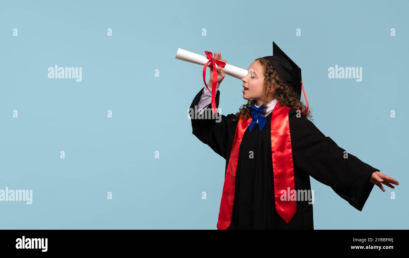 Young girl in graduation gown holding diploma like a telescope ...