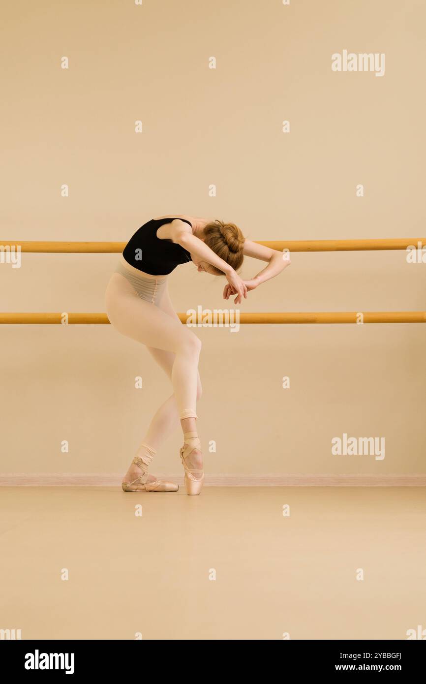 Ballet dancer stretching at the barre, leaning forward with a curved ...