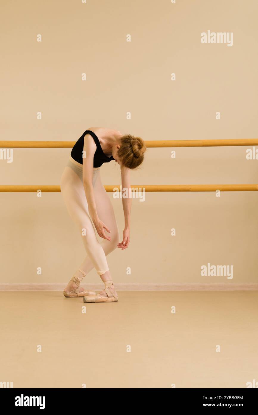 Ballet dancer leaning forward with her arms hanging, in a gentle ...