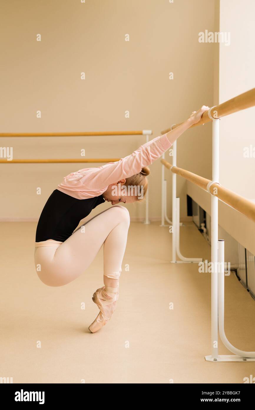Ballet dancer balancing on pointe at the barre, stretching and curling ...