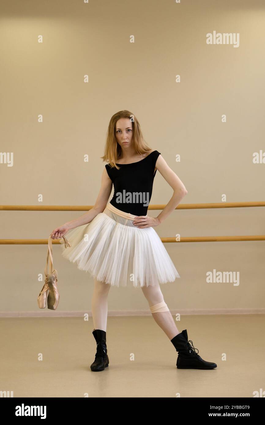 Ballerina posing with pointe shoes in hand, blending modern and classic ...