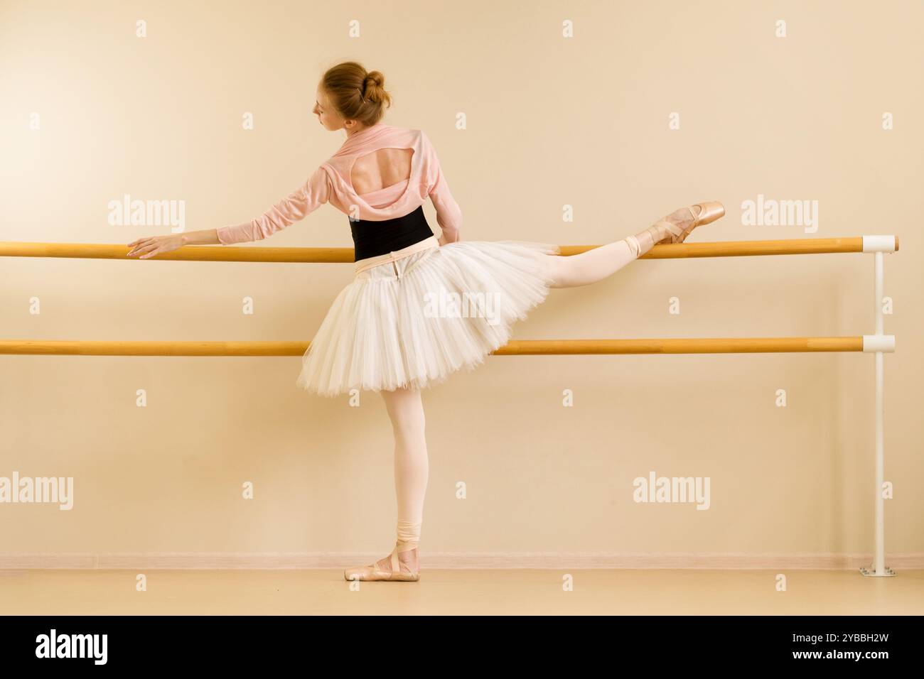 Ballet dancer practicing leg stretch while balancing on pointe shoes ...