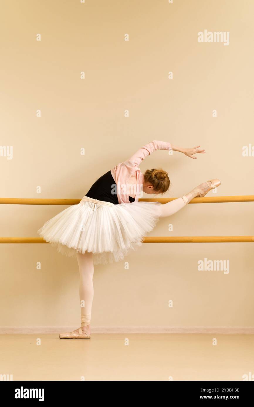 Ballerina performing deep leg stretch at barre during practice ...